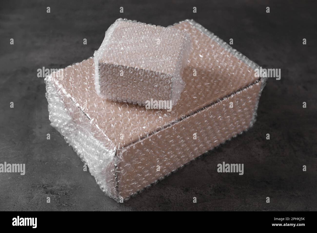 Cardboard boxes covered with bubble wrap on dark grey table Stock Photo ...