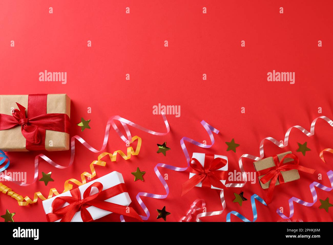 Colorful serpentine streamers, gift boxes and confetti on red ...