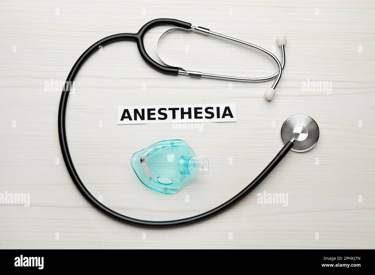 Word Anesthesia, mask and stethoscope on white wooden table, flat lay ...