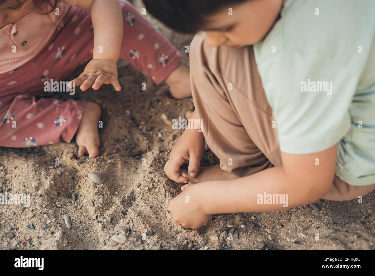 Little kids playing in a sandbox with sand, digging with hands. two ...