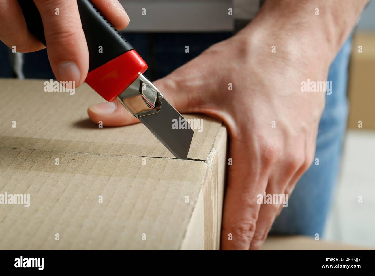 Man using utility knife to open parcel, closeup Stock Photo - Alamy