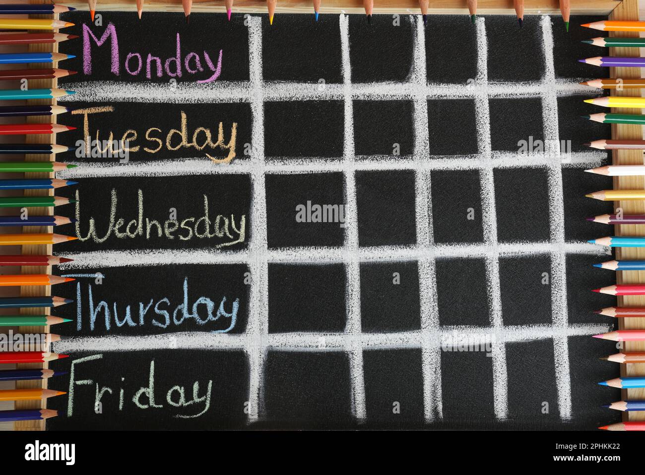Colorful pencils and drawn weekly school timetable on black chalkboard ...