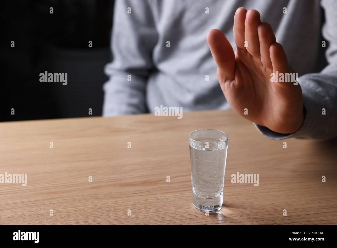 Man refusing to drink vodka at wooden table, closeup. Alcohol addiction ...