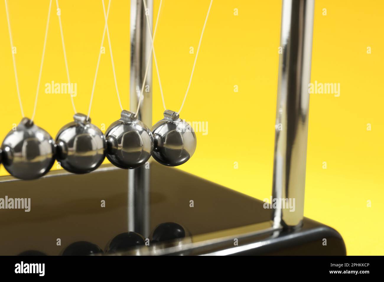 Newton's cradle on yellow background, closeup. Physics law of energy ...