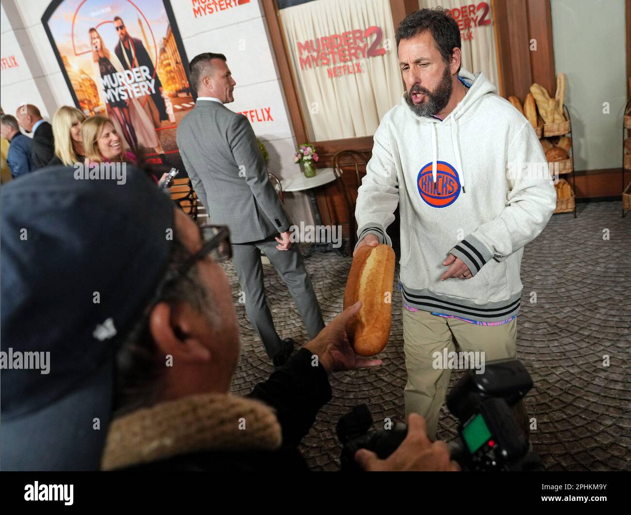 Los Angeles, USA. 28th Mar, 2023. Adam Sandler hands a loaf of bread to ...