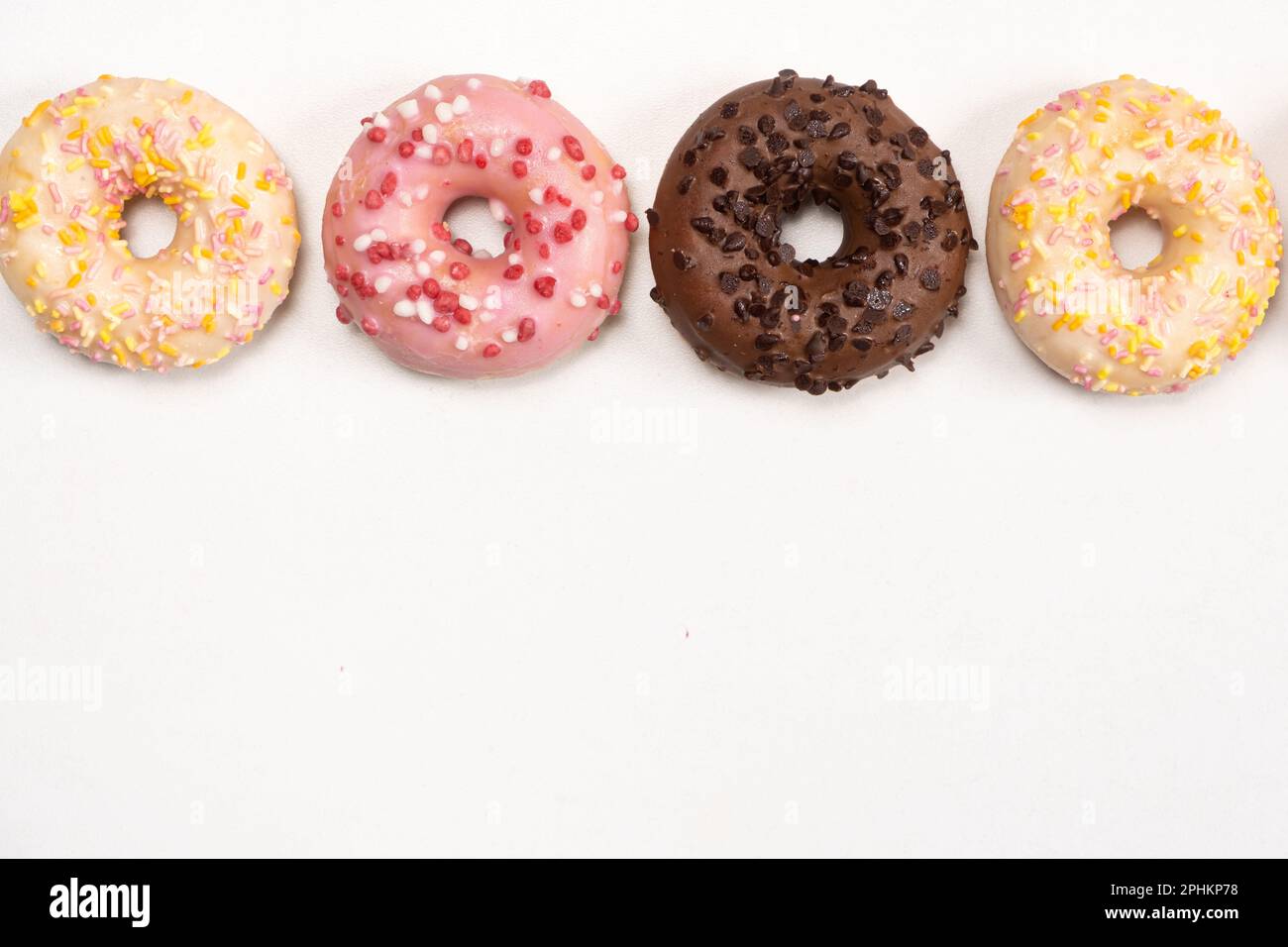 Four donuts in a row - white, pink and chocolate on a white background ...
