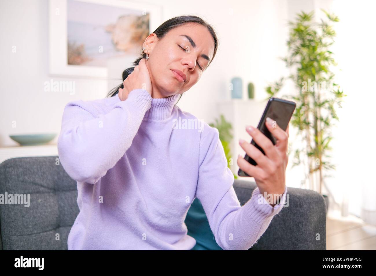 Woman holding mobile phone suffering back pain caused by bad posture ...