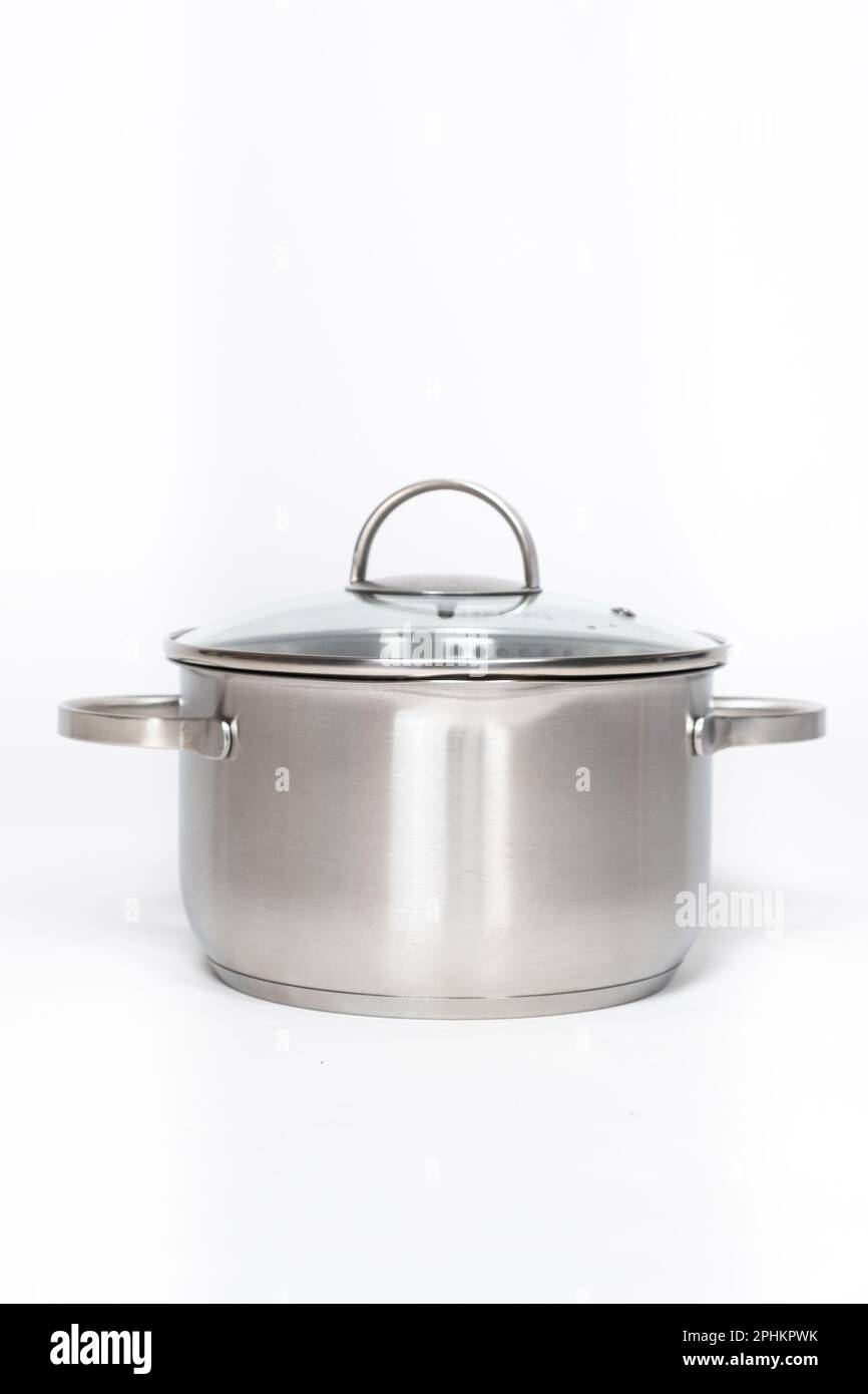 Stainless steel pot with glass lid and drain spout on a white ...
