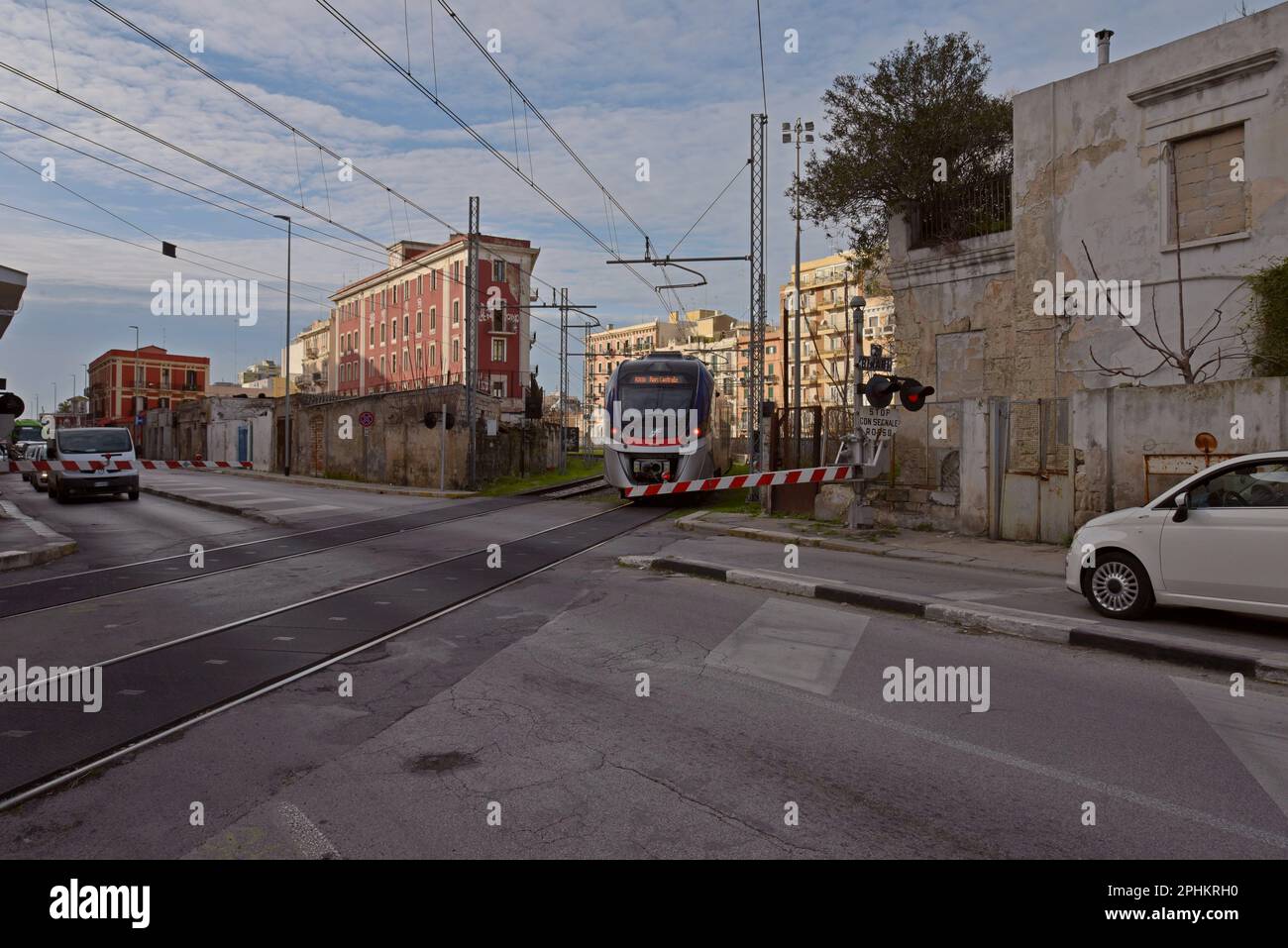 A regional Trenitalia train at a level crossing on the approach to Bari ...