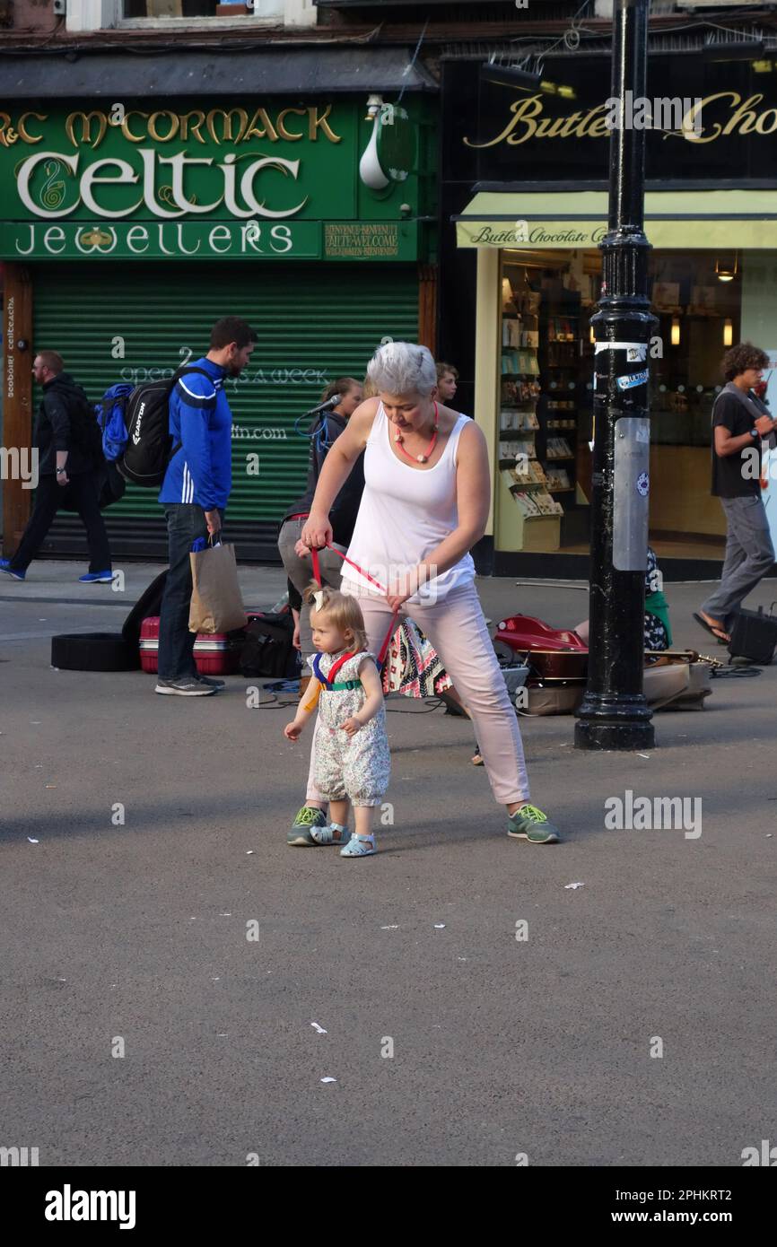 Toddler wearing a child harness for safety in busy Grafton Street ...