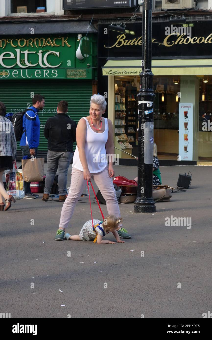 Toddler wearing a child harness for safety in busy Grafton Street ...