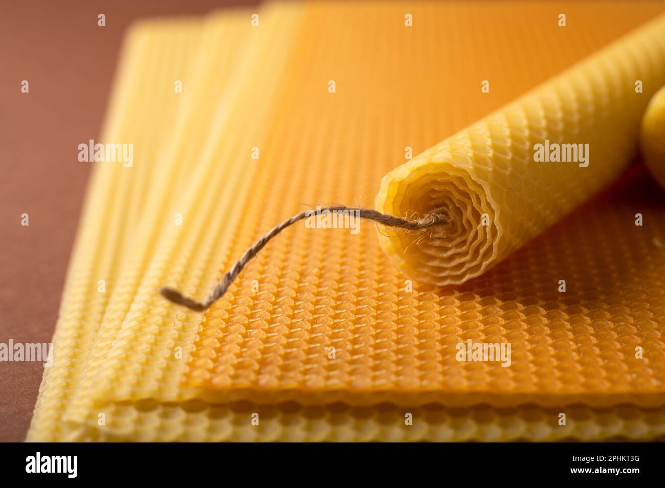 Beeswax honeycomb candle sheets and jute thread on brown background. Making candle step by step ...