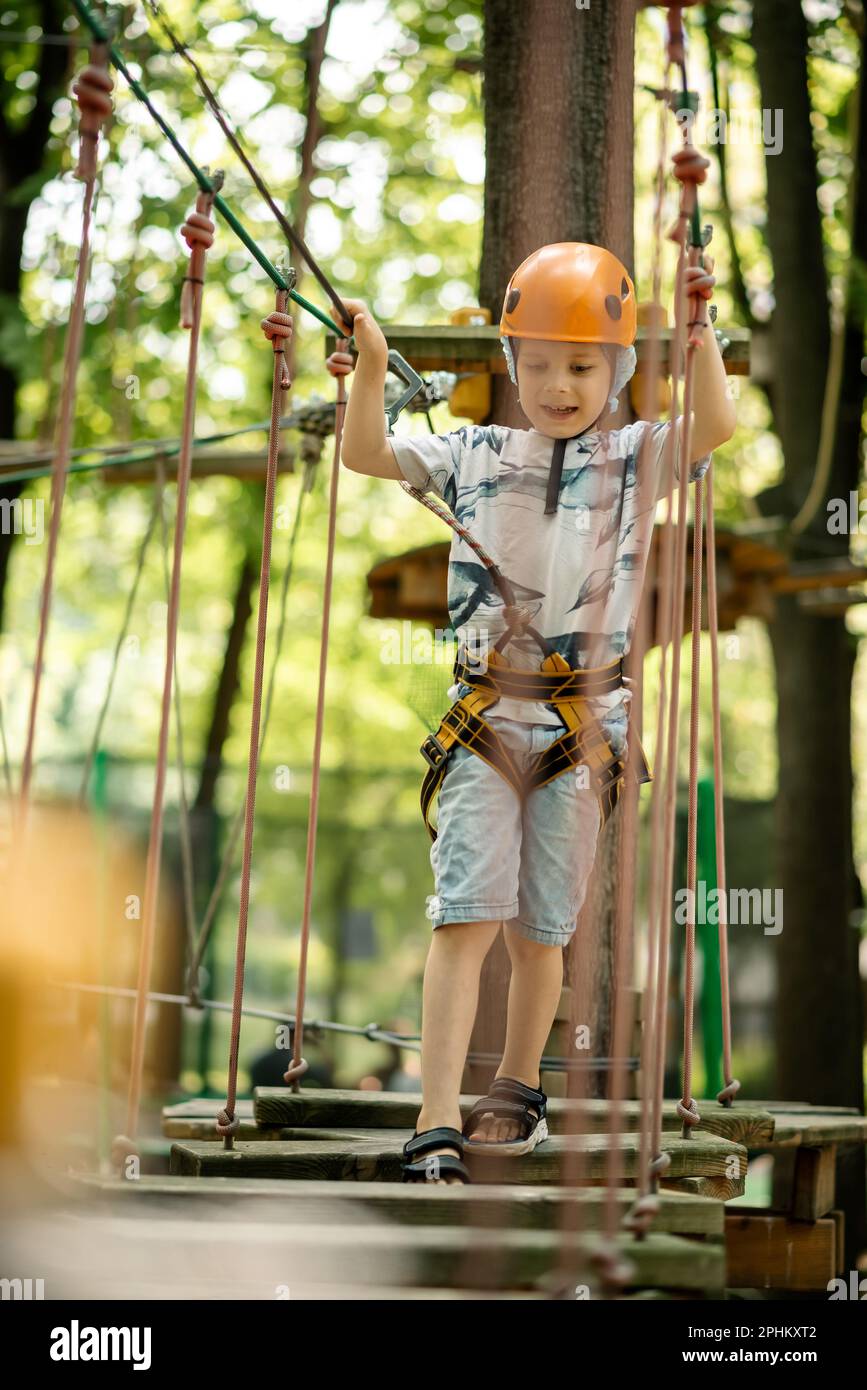 Rope park for children. A young boy in a flap climbs obstacles. Active ...