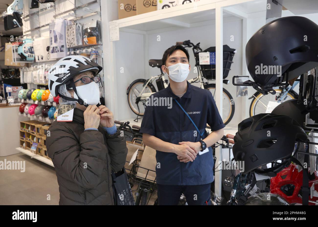 An employee of Cycle Base Asahi shows bicycle helmets in Shibuya Ward ...