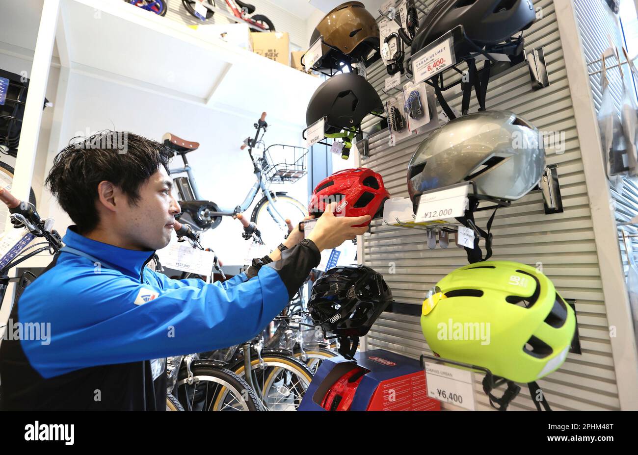An employee of Cycle Base Asahi shows bicycle helmets in Shibuya Ward ...