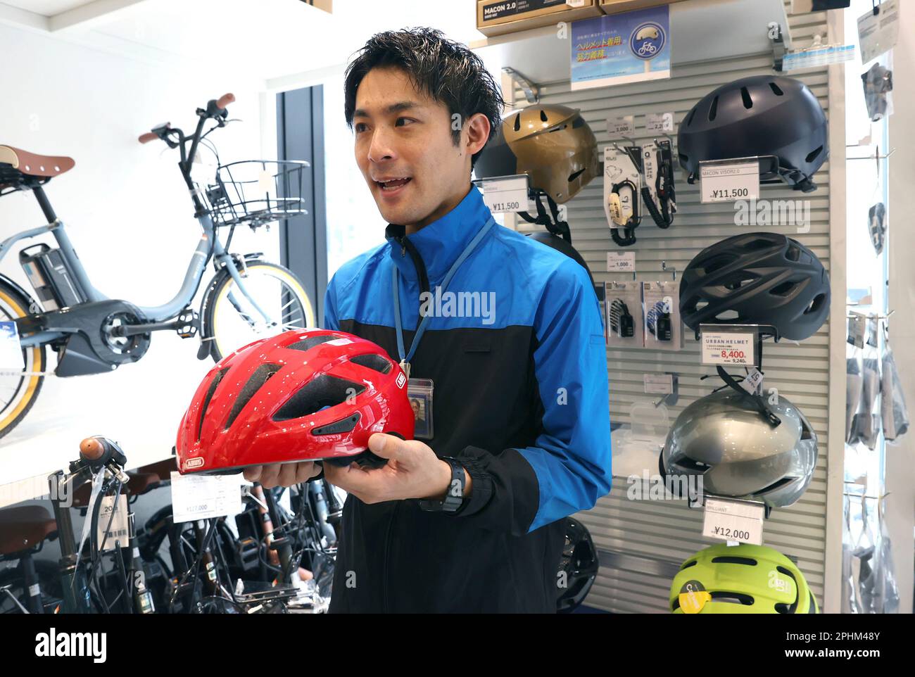 An employee of Cycle Base Asahi shows bicycle helmets in Shibuya Ward ...