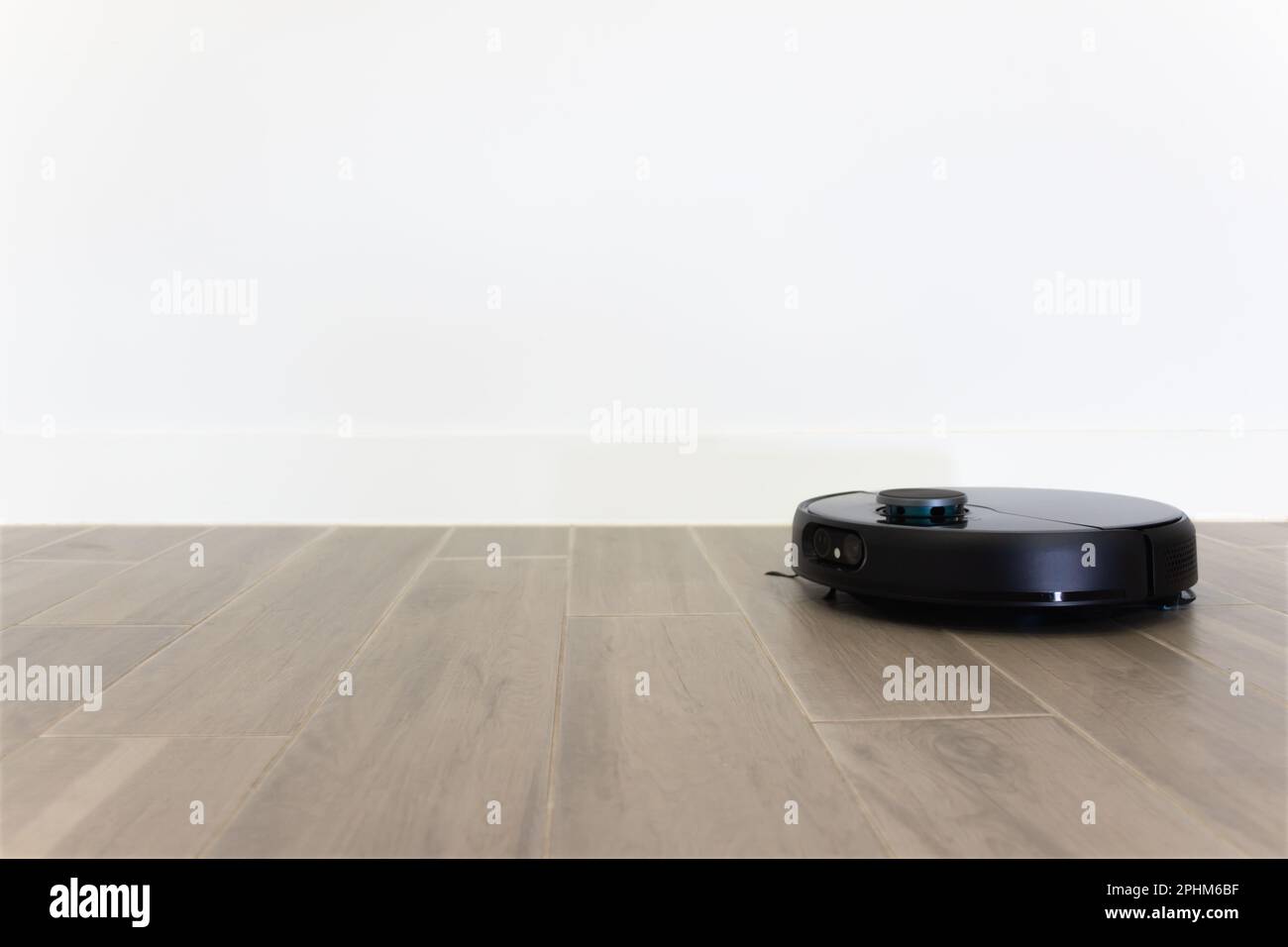 A futuristic robotic vacuum cleaner in a minimalist white-walled room ...
