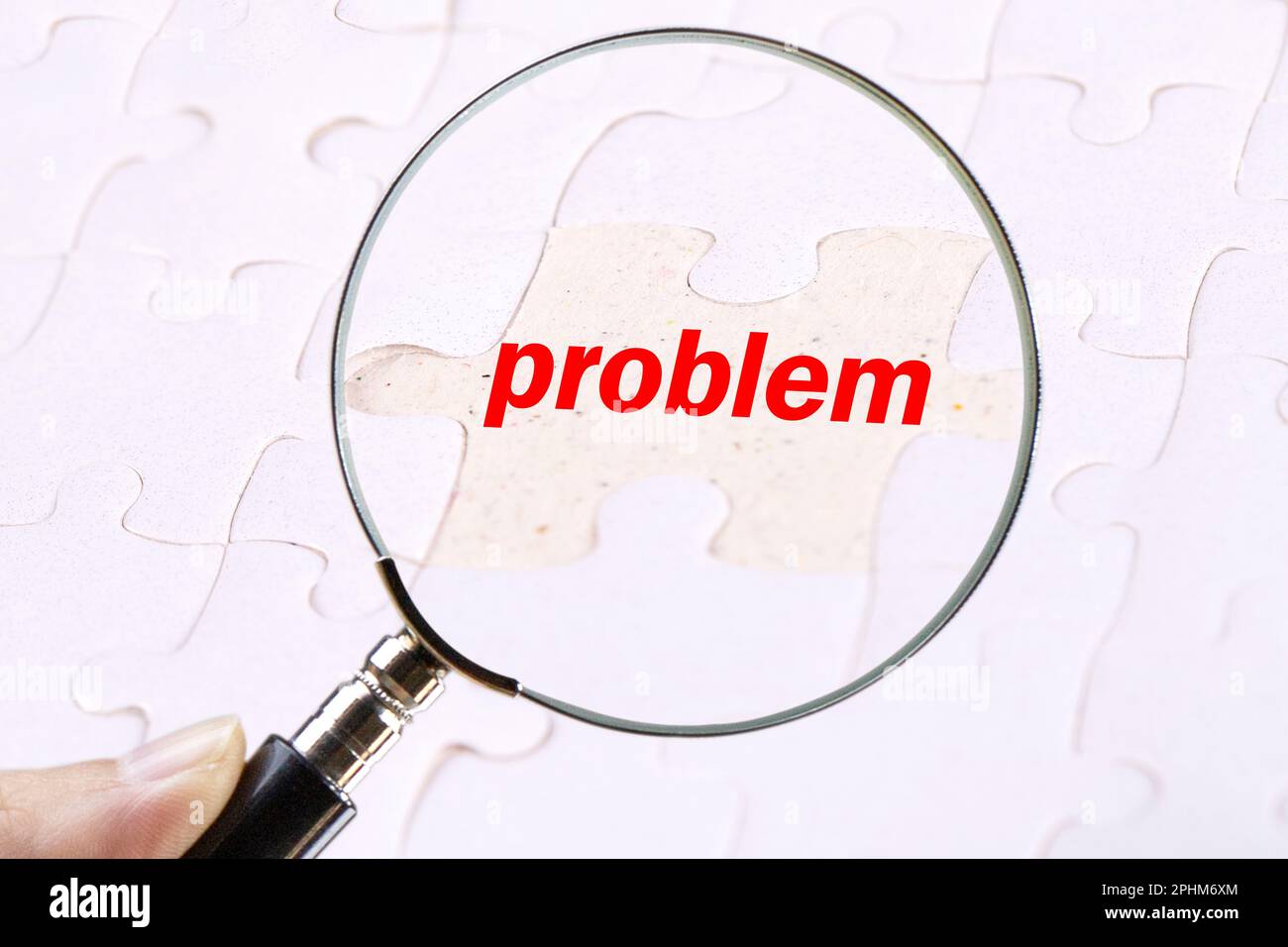 Hand with magnifying glass searching for a piece of jigsaw puzzle with ...