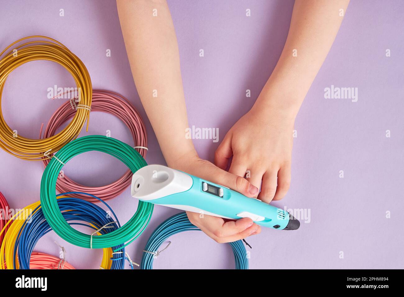 Children hands holding 3d pen over the colorful heap of plastics. Hobby ...