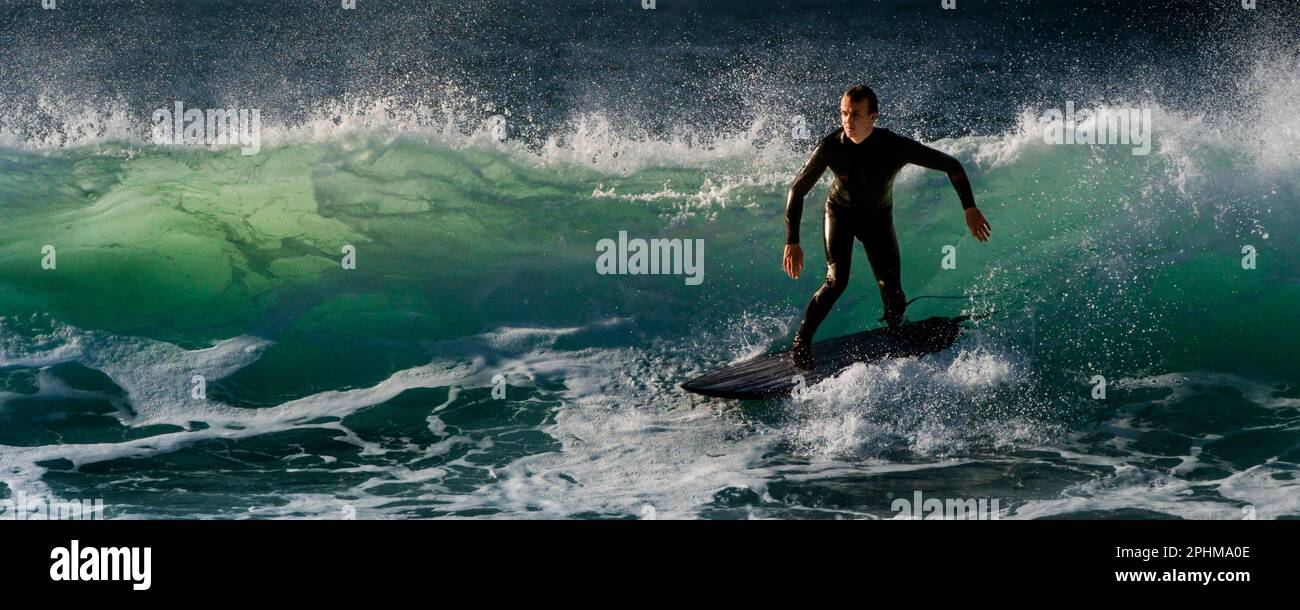 A panoramic image of surfing action as a male surfer rides a wave at ...