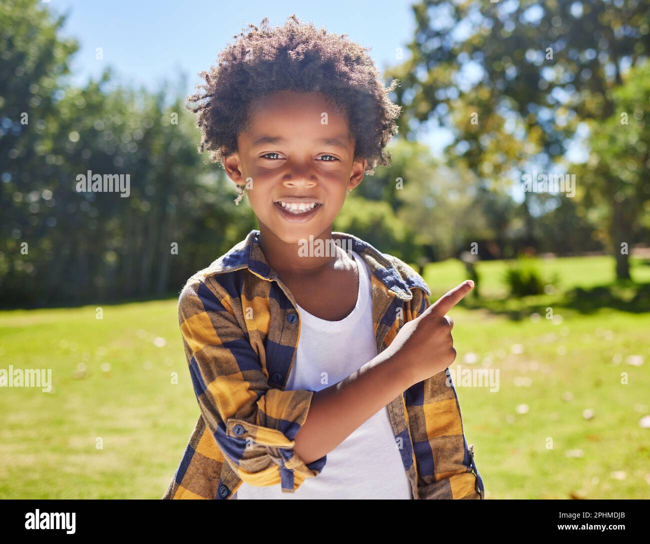 African boy, pointing and park portrait with smile, happiness or ...