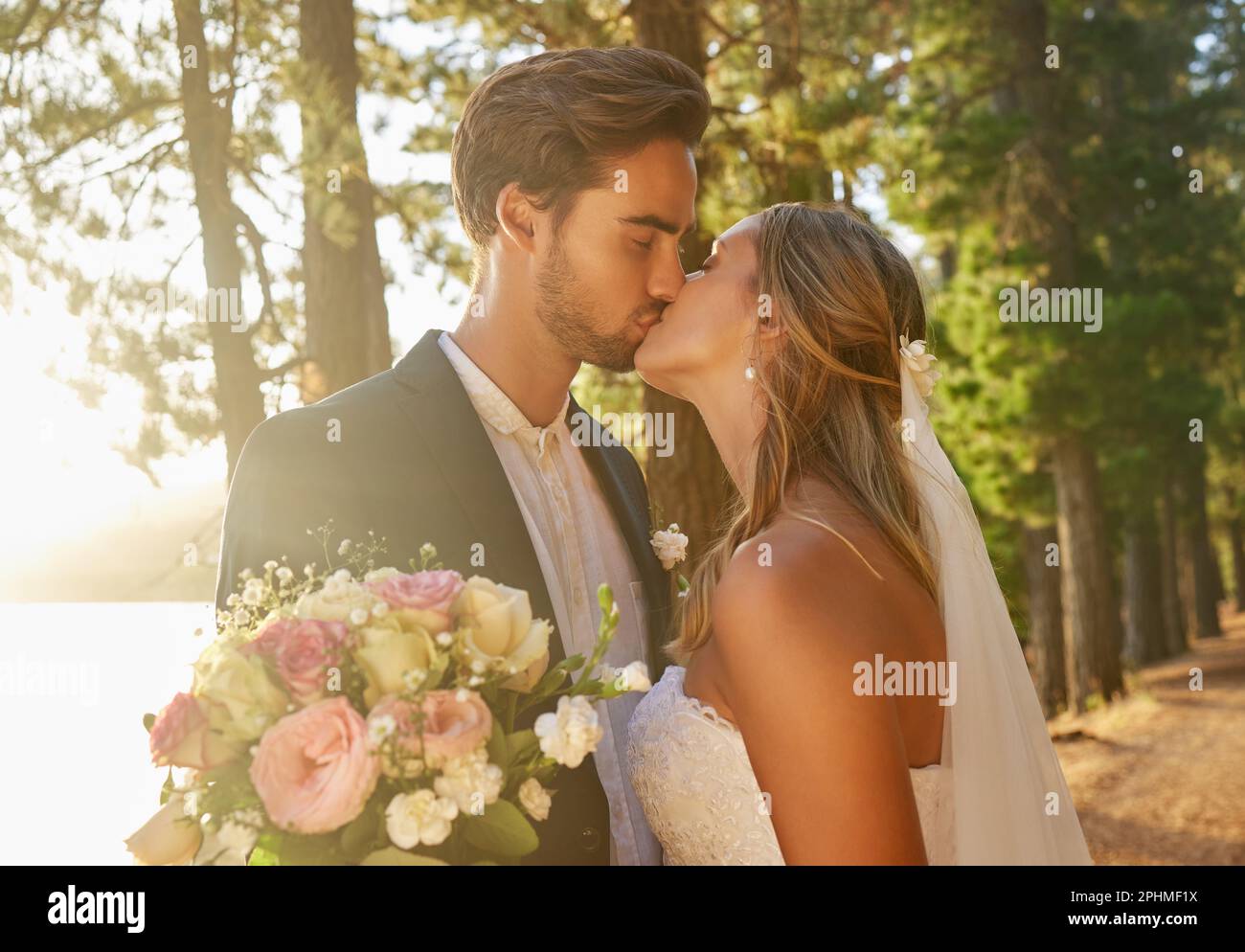 Wedding, married and couple kiss in park, forest and nature for celebration of love, care and ...