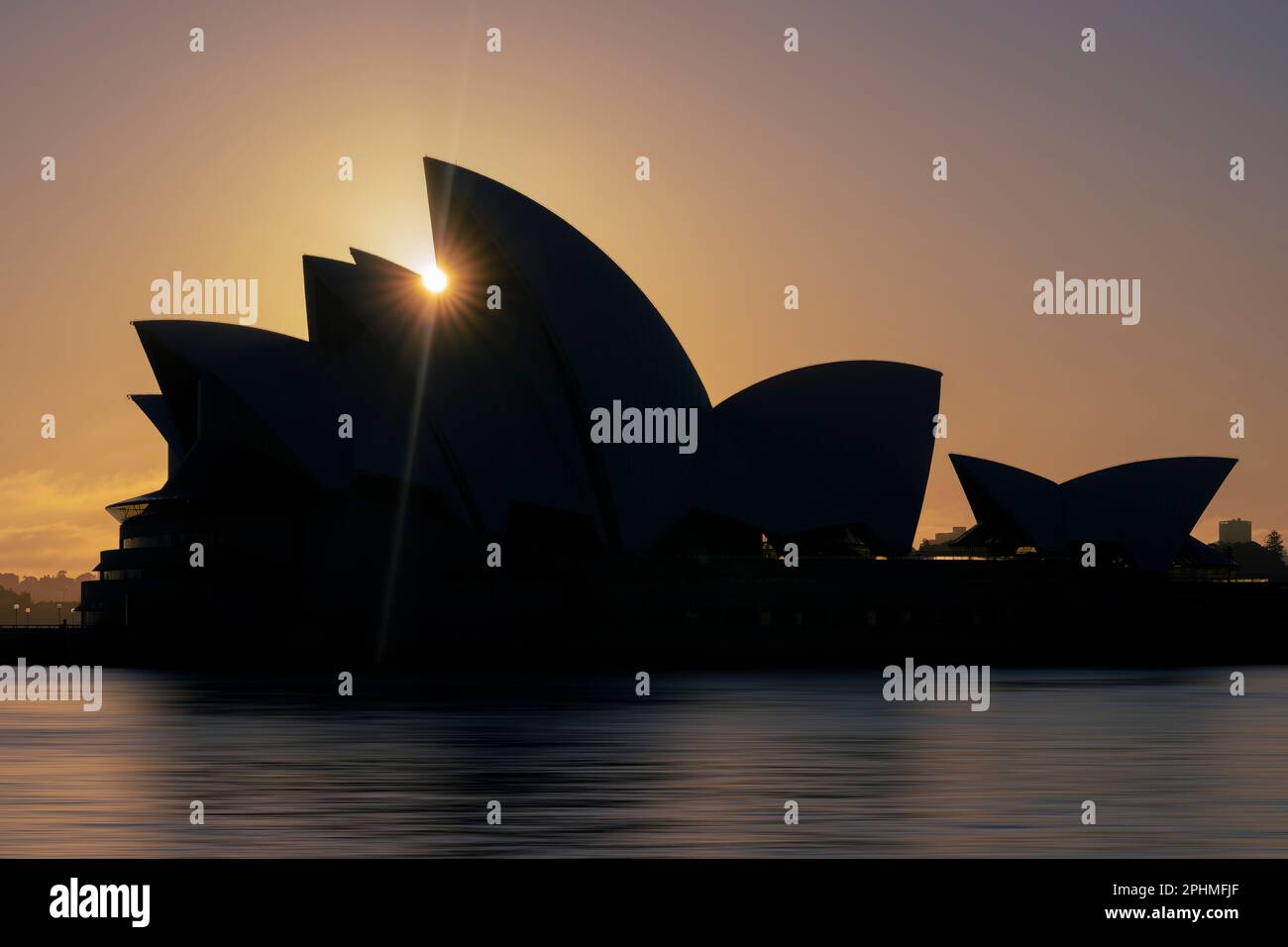 An idyllic scene of Sydney Opera House with the sun setting behind it ...