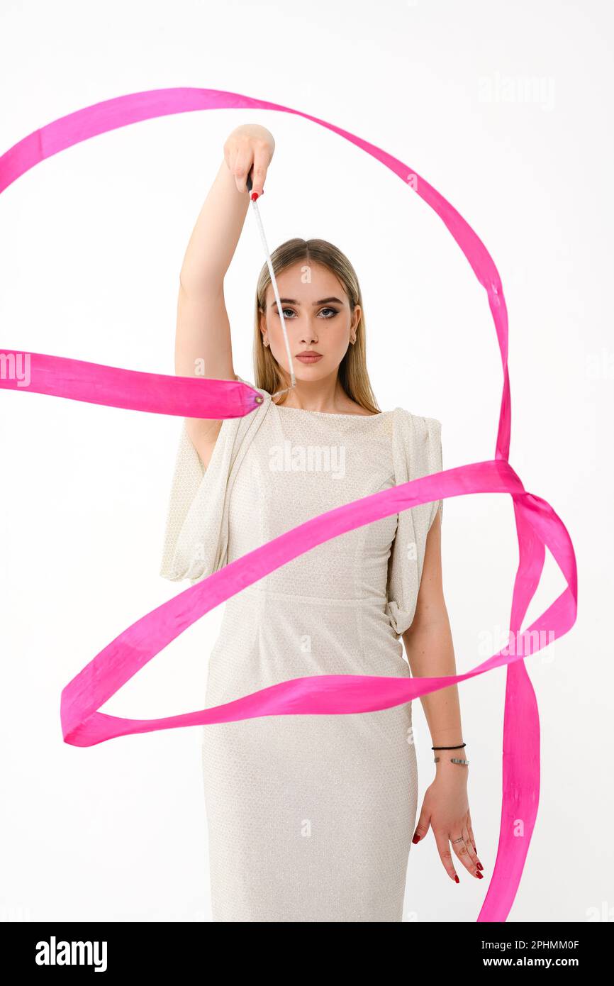 Girl gymnast dressed in an evening dress with a pink ribbon on a white ...