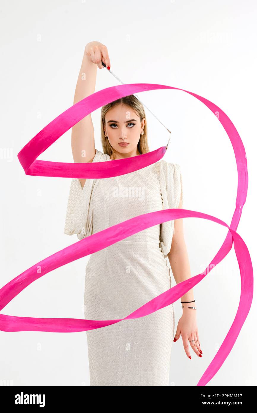 Girl gymnast dressed in an evening dress with a pink ribbon on a white ...