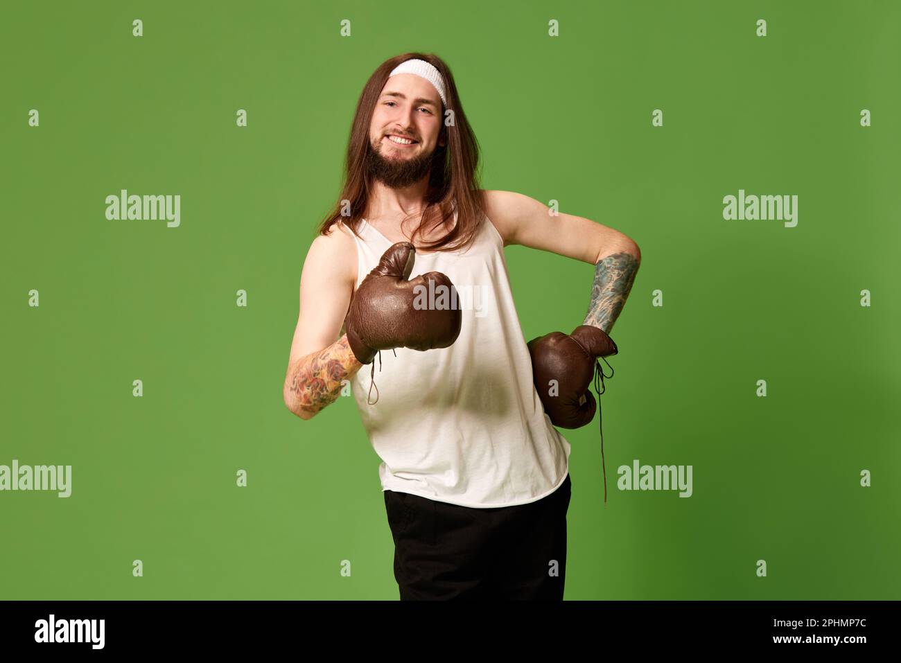Portrait of young man with long brown hair posing in singlet and ...