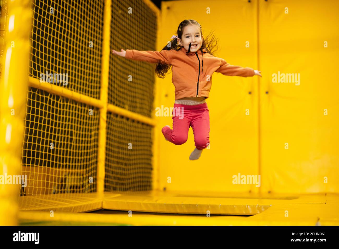 Little girl kid jumping on trampoline at yellow playground park. Child ...