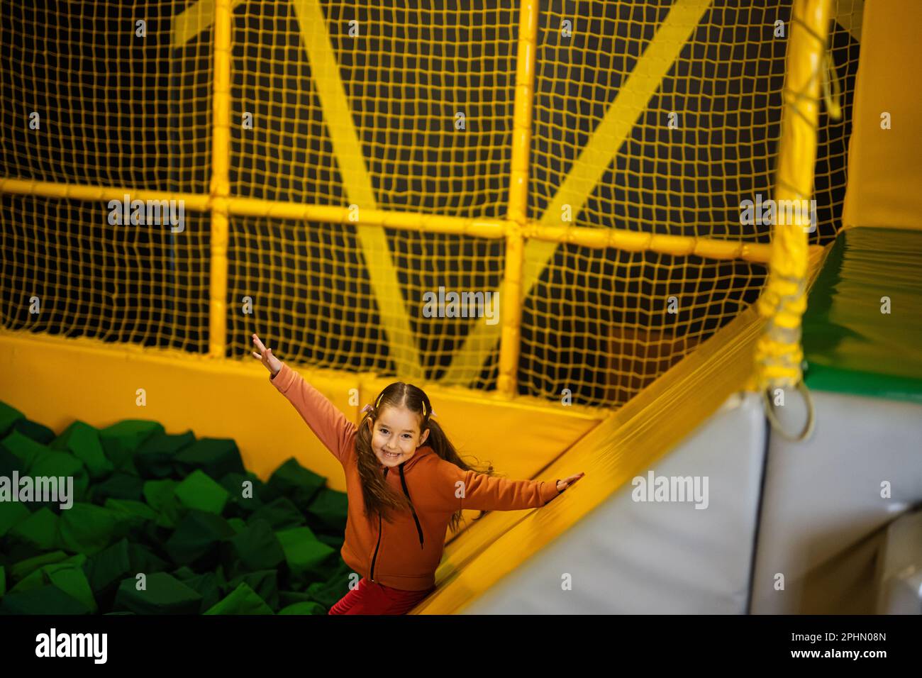 Little girl kid slide to green soft cubes at yellow playground park ...