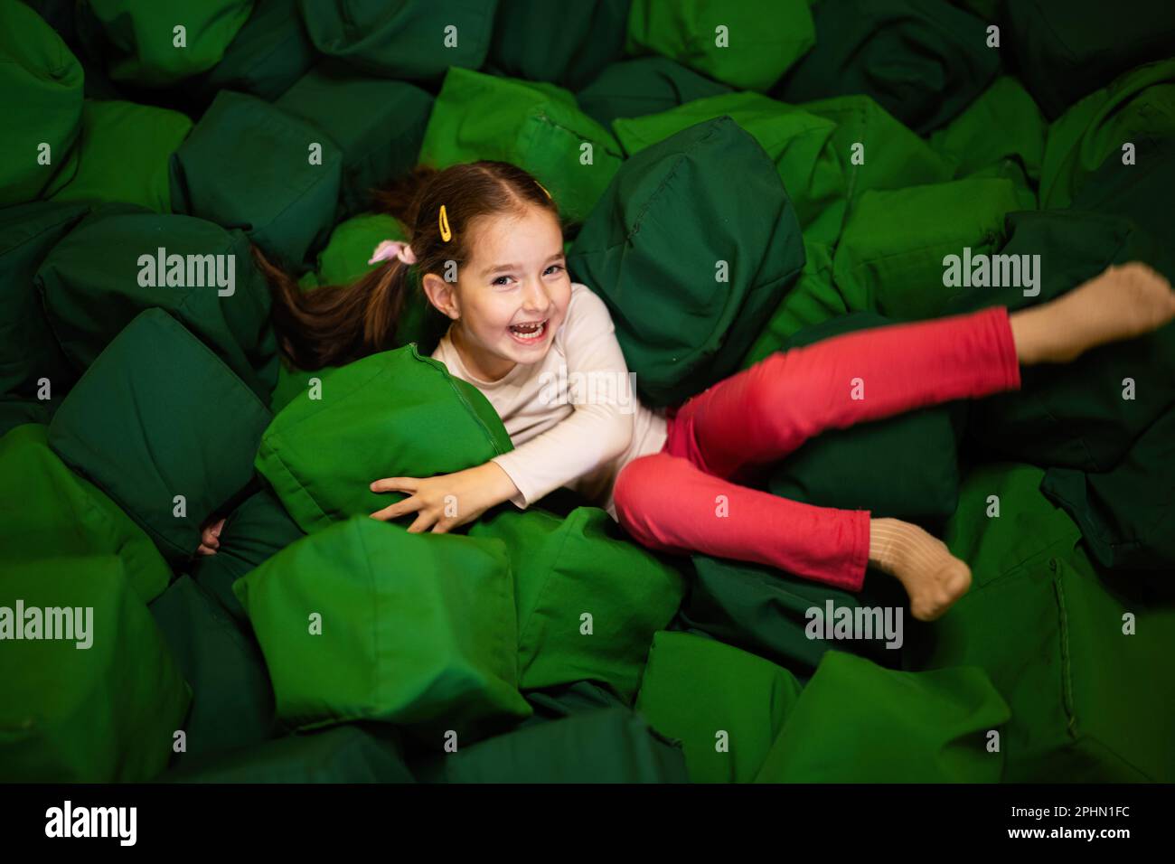 Little girl kid lies on green soft cubes at playground park. Child in ...