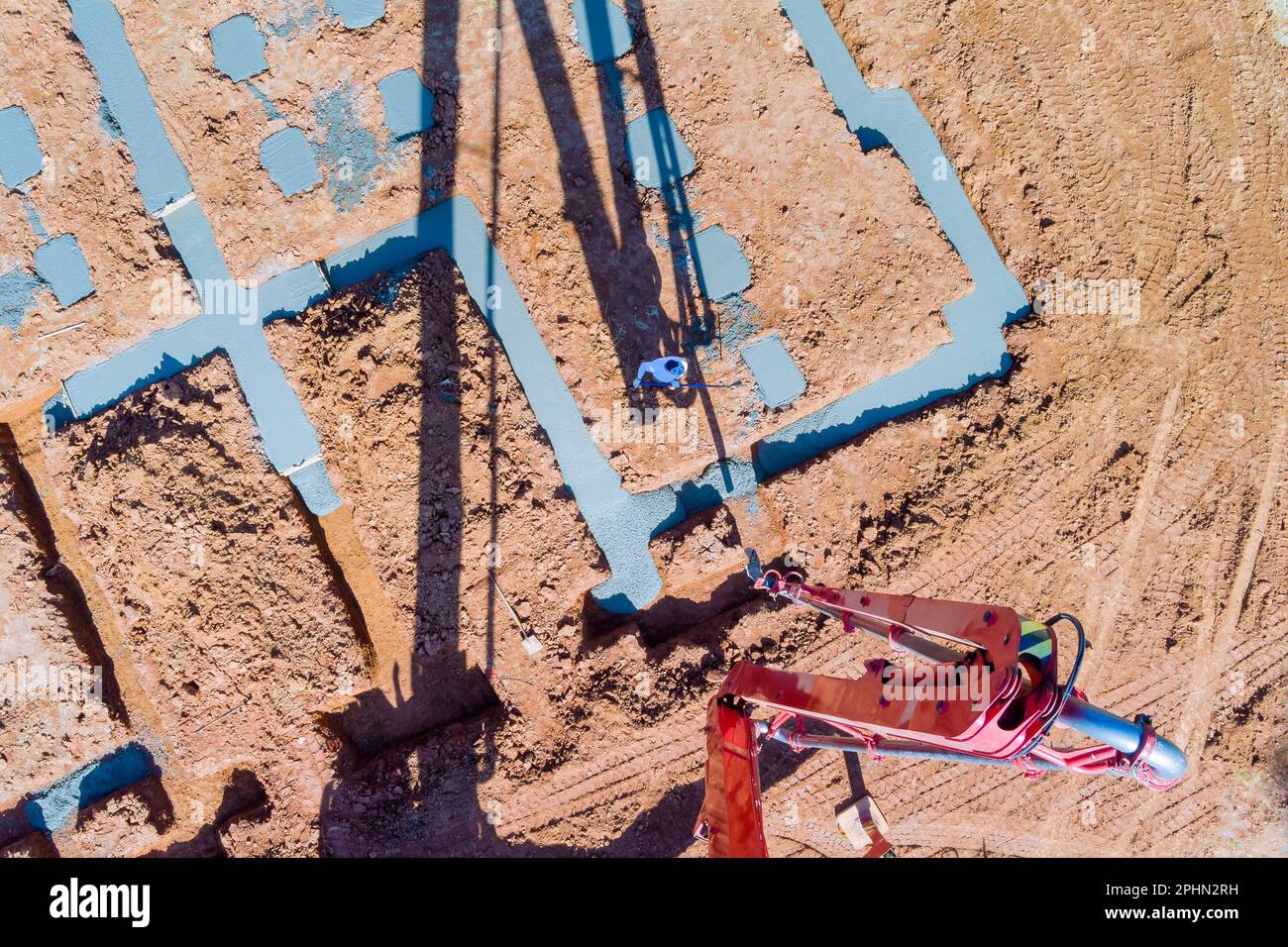 Foundation of house is constructed by pouring concrete strips using an ...