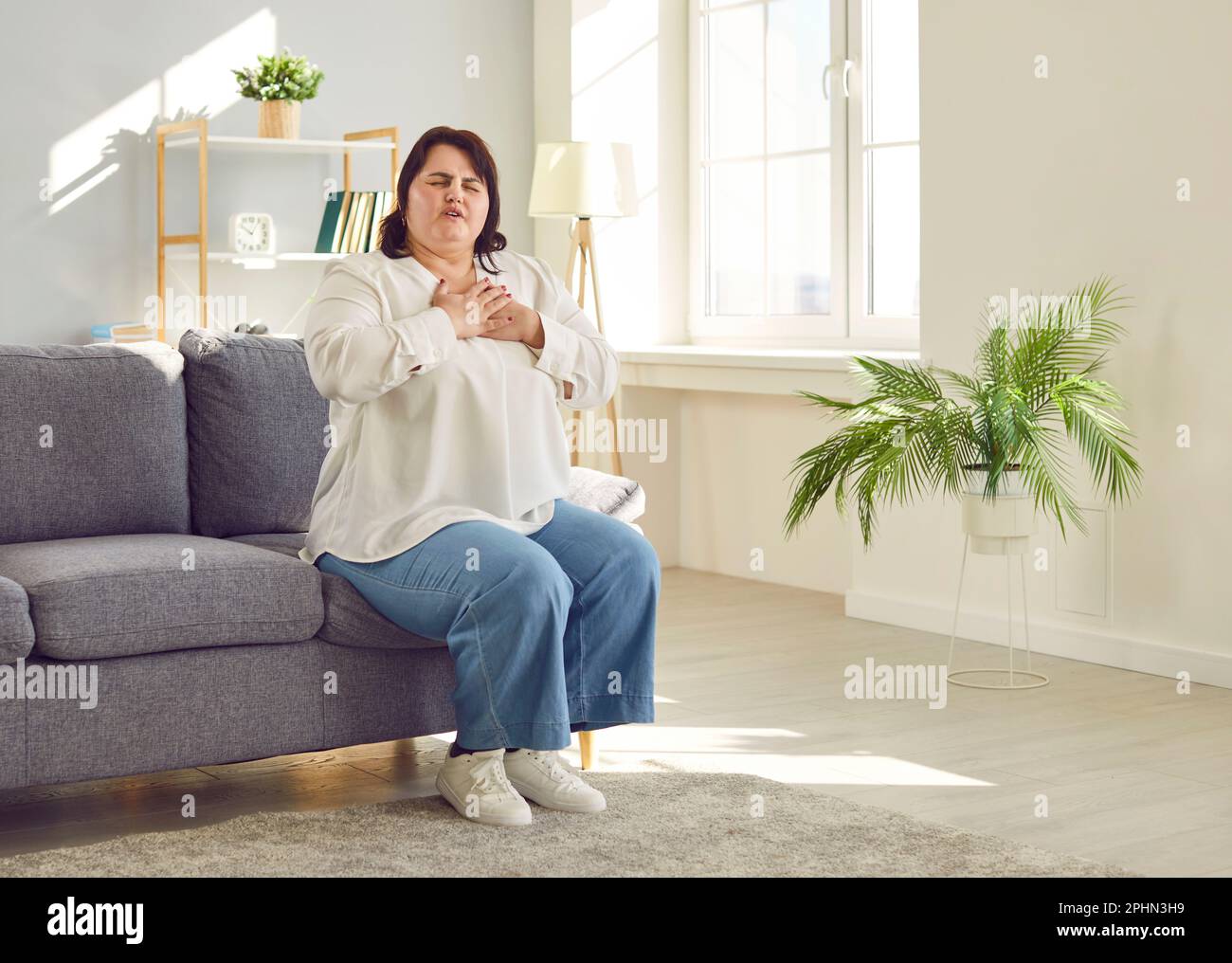 Young overweight fat woman sitting on the couch suffering from heart ...