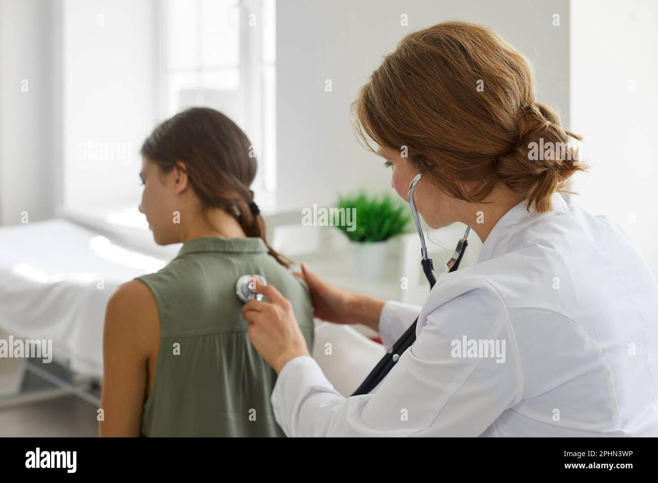 Female doctor with a medical stethoscope examining the lungs of a ...