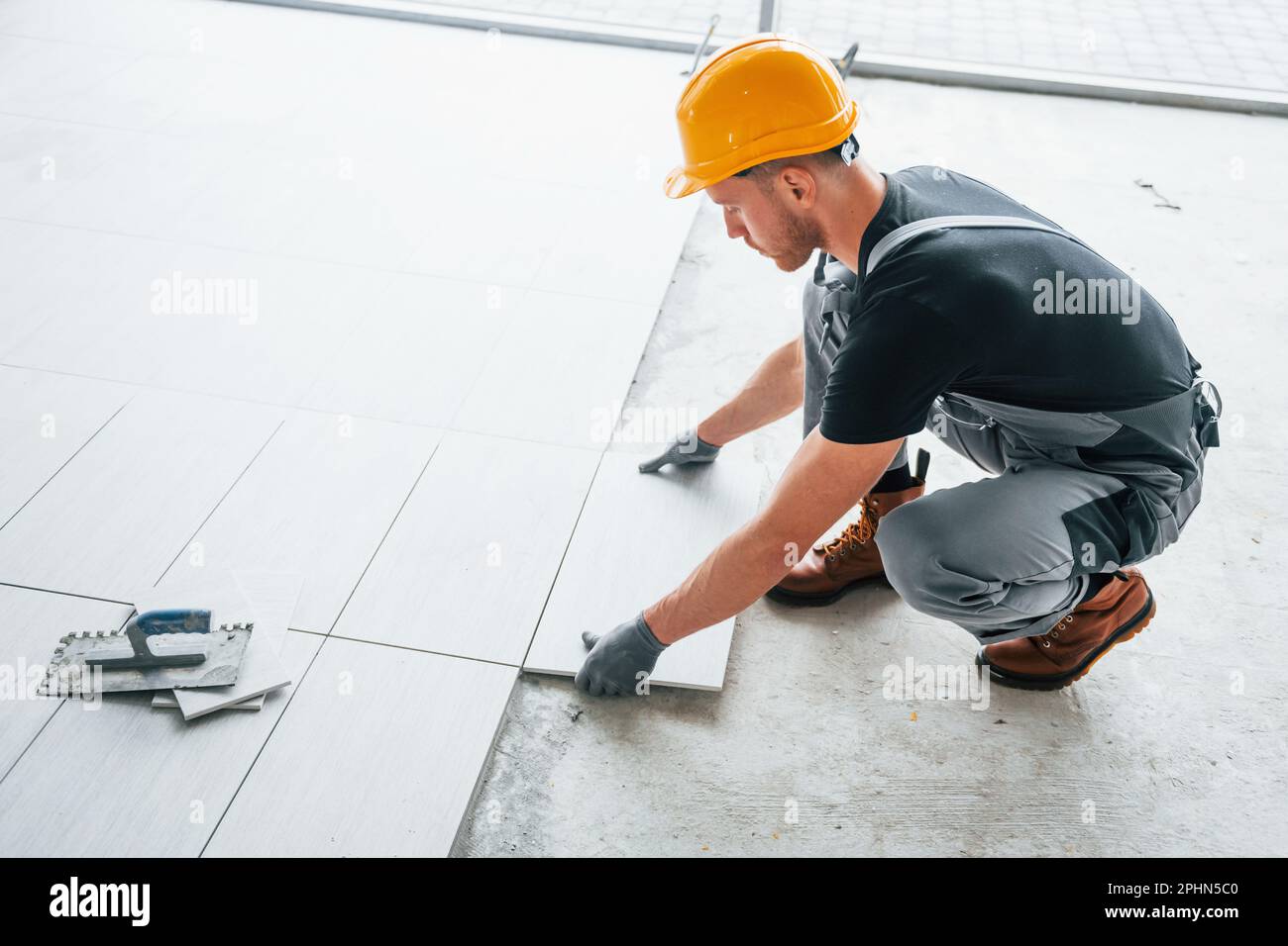 Installation of plates. Man in grey uniform and orange hard hat works ...