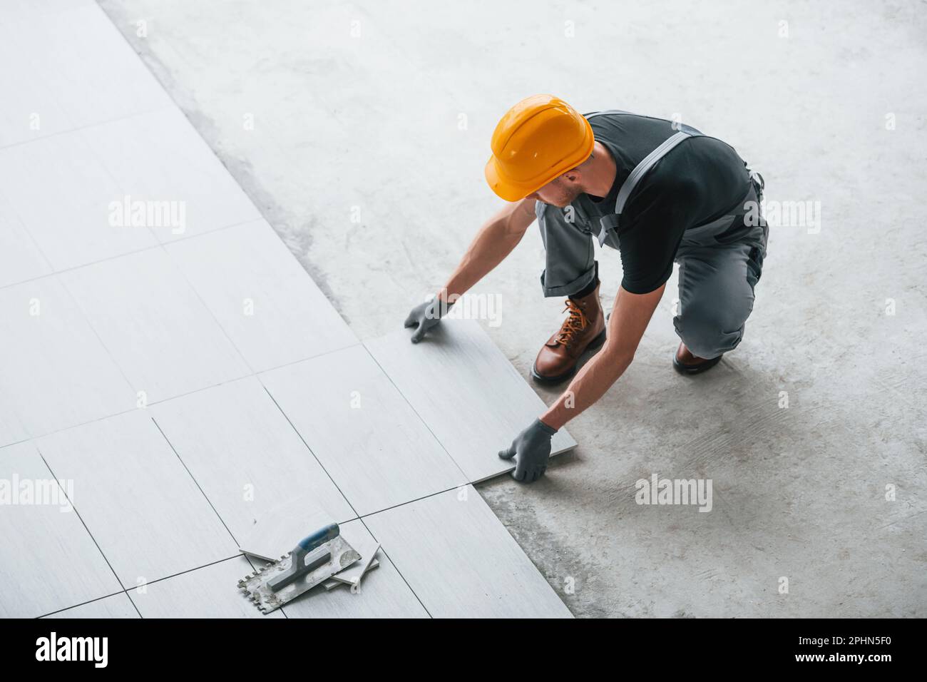 Installation of plates. Man in grey uniform and orange hard hat works ...