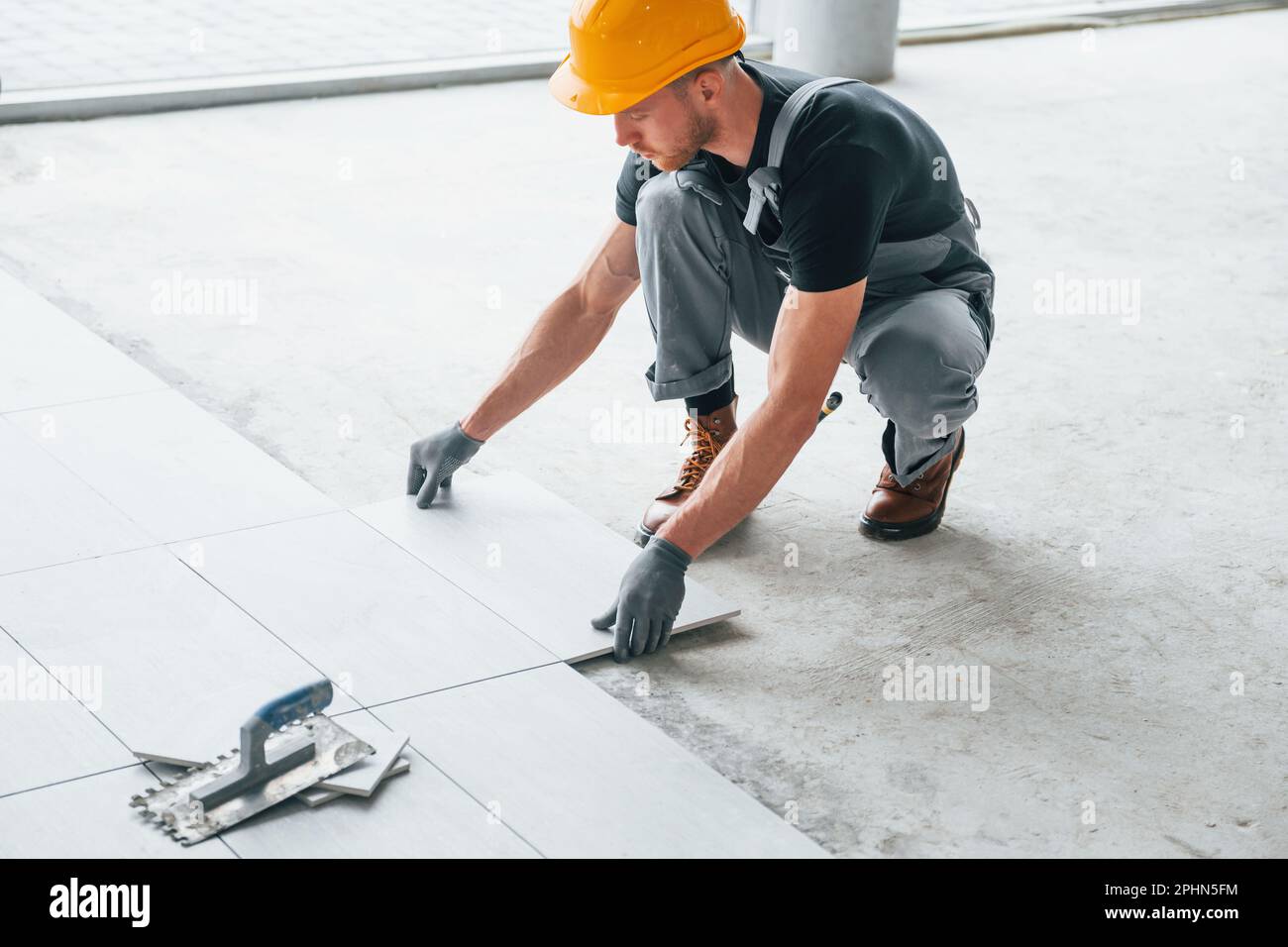 Installation of plates. Man in grey uniform and orange hard hat works ...