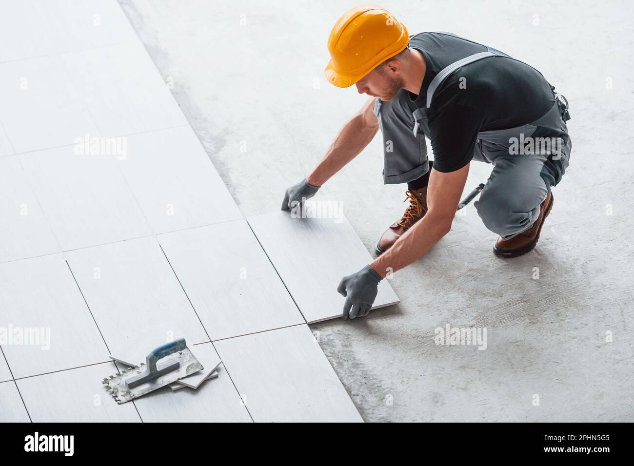 Installation of plates. Man in grey uniform and orange hard hat works ...