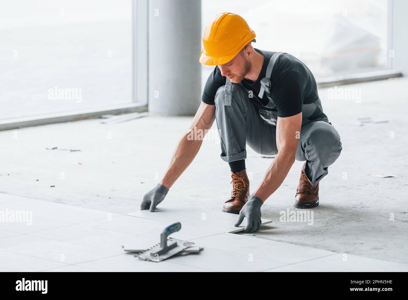 Installation of plates. Man in grey uniform and orange hard hat works ...