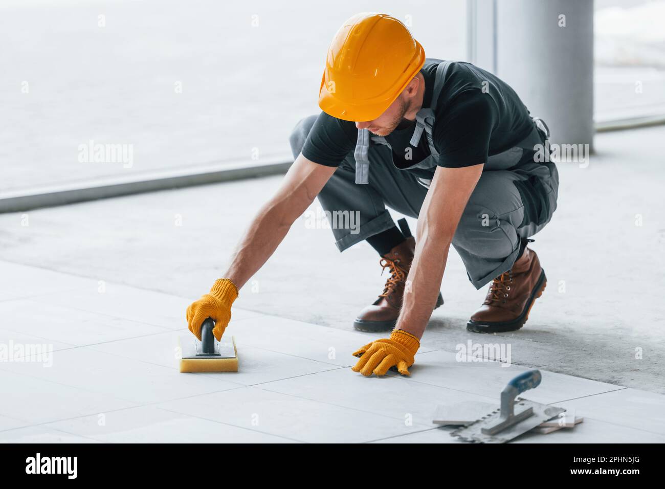 Installation of plates. Man in grey uniform and orange hard hat works ...