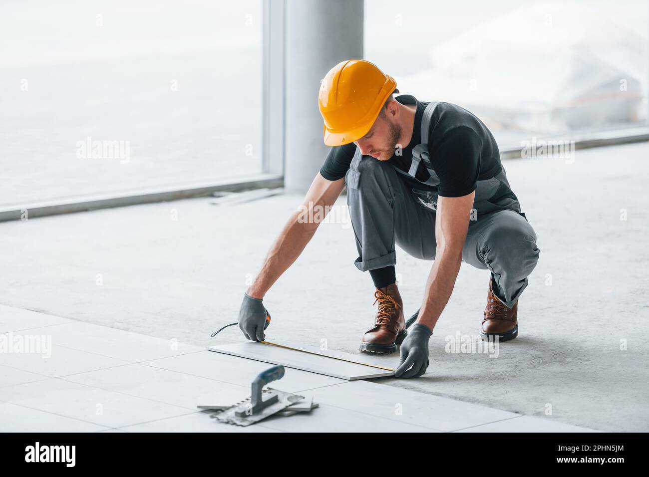 Installation of plates. Man in grey uniform and orange hard hat works ...