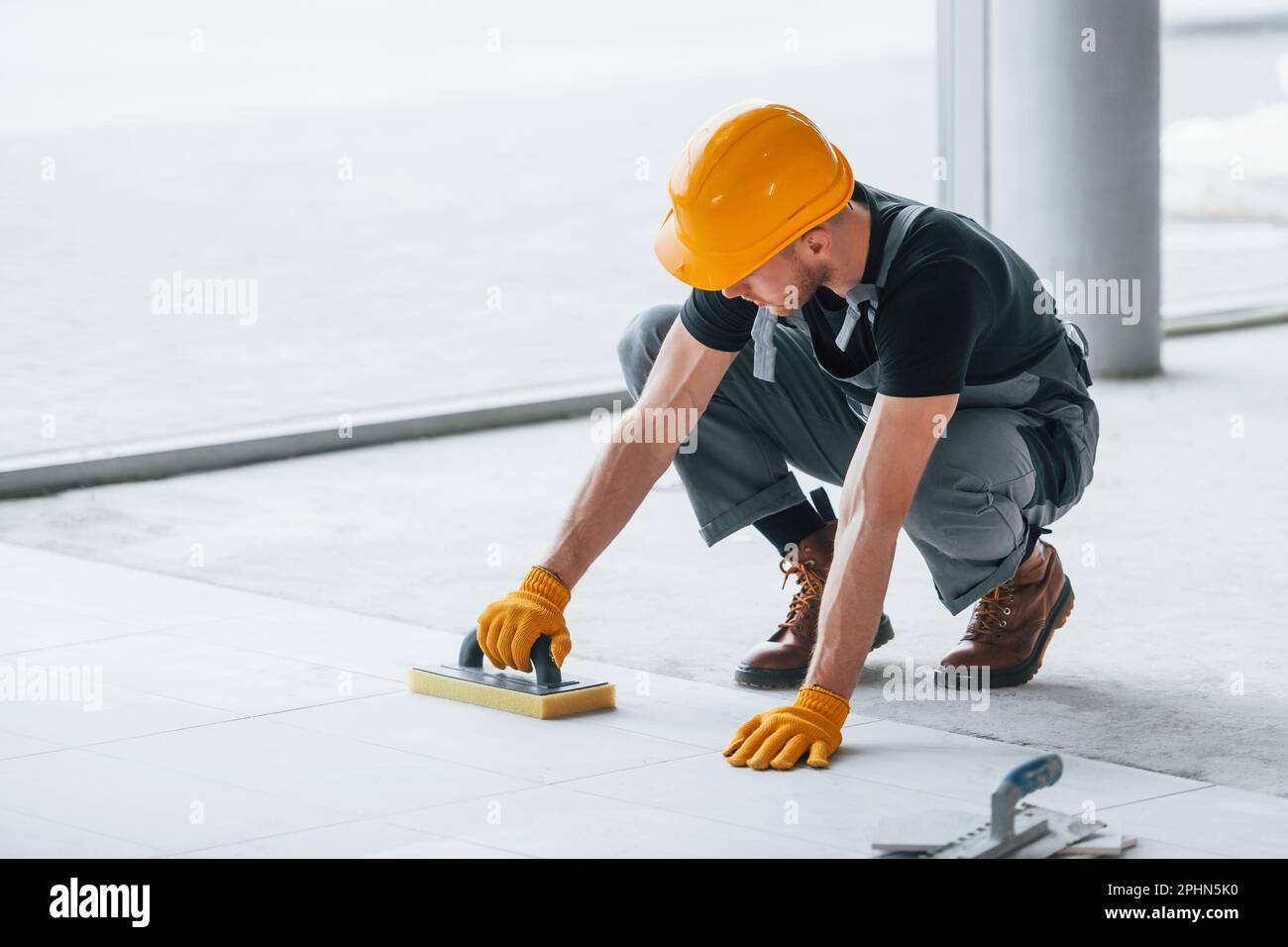 Installation of plates. Man in grey uniform and orange hard hat works ...