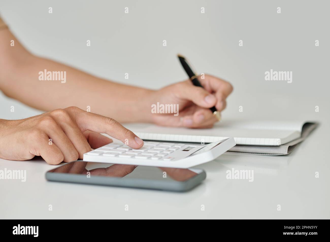 Hands of businessman making calculations and taking notes in planner ...