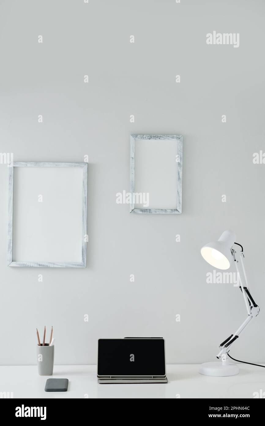Empty photo frames on wall above office desk with tablet computer and ...