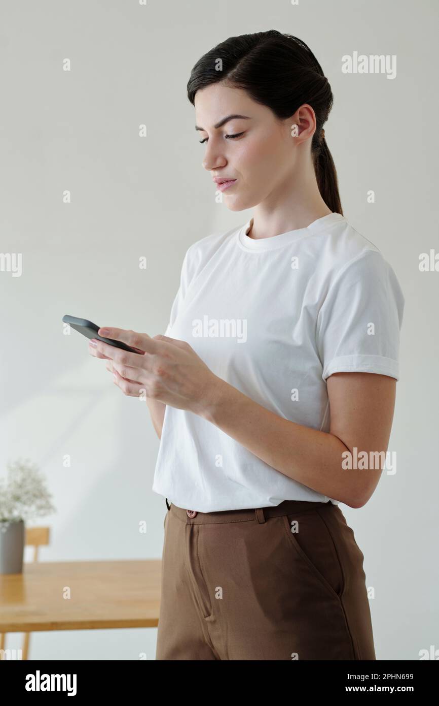 Young woman answering text messages from colleague when working from ...