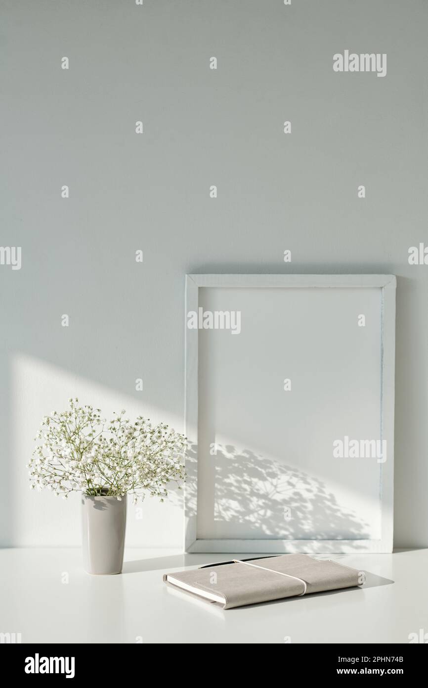 Empty picture frame next to vase with flowers and planner on desk Stock ...