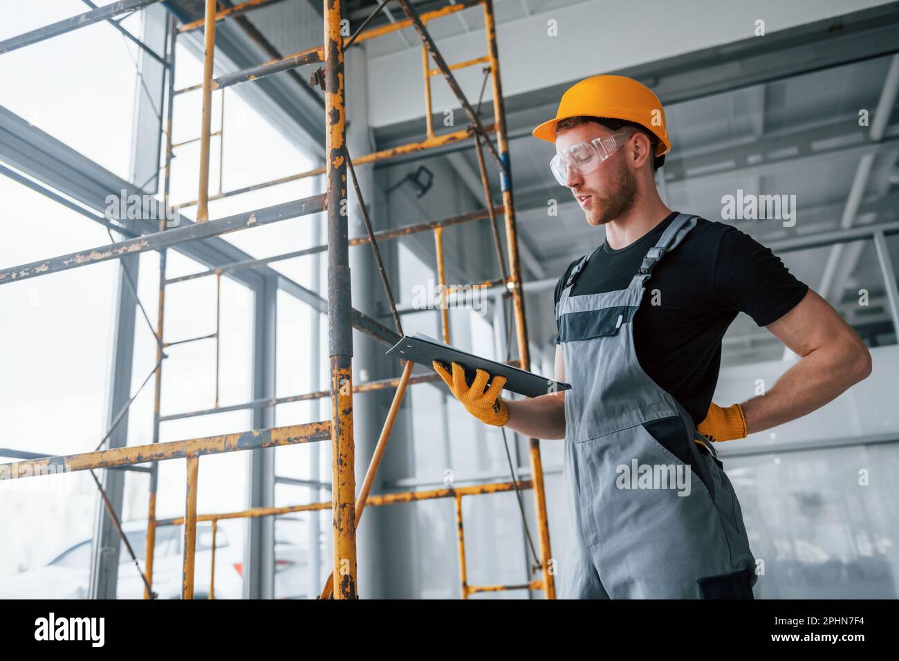 Engineer in grey uniform with notepad in hands works indoors in modern ...