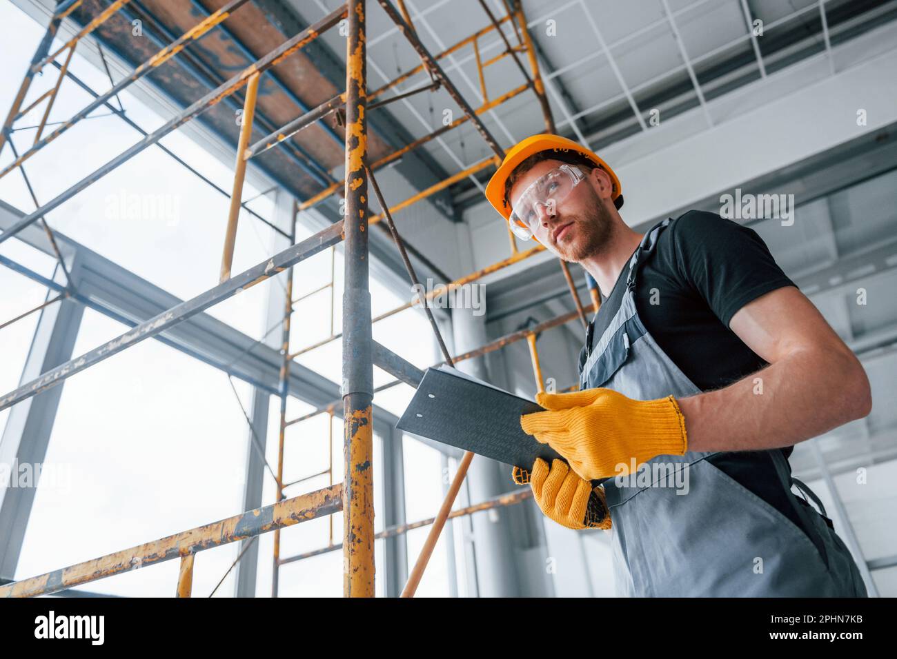 Engineer in grey uniform with notepad in hands works indoors in modern ...